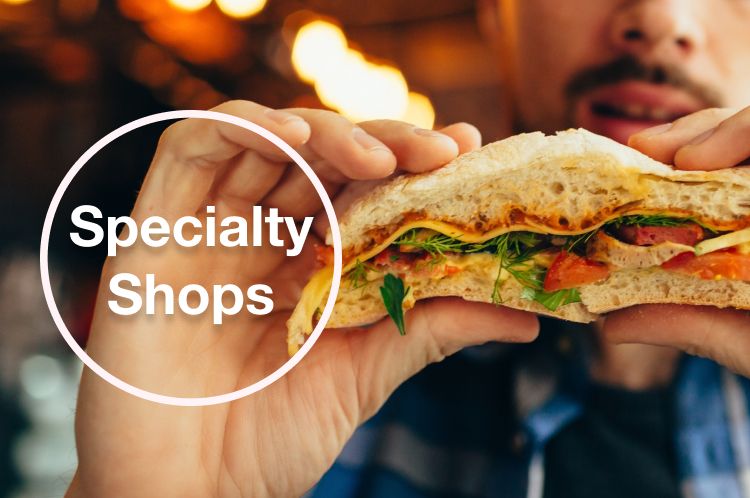 Specialty Shops - Two hands holding a half of a sandwich with a person ...
